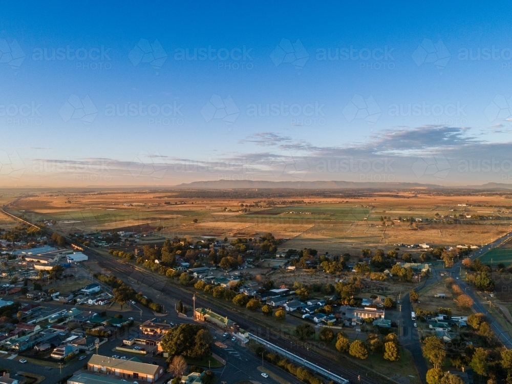 Image of Sunrise light over edge of rural town with train line passing ...