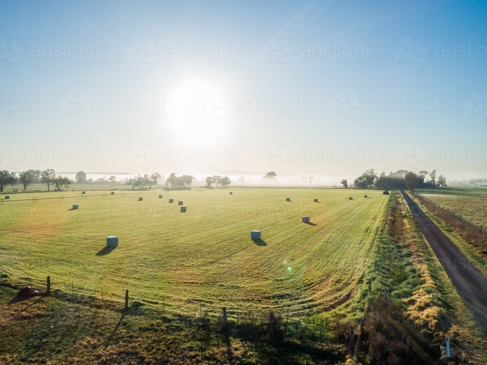 Image of sunrise over silage bales in farm paddock - Austockphoto