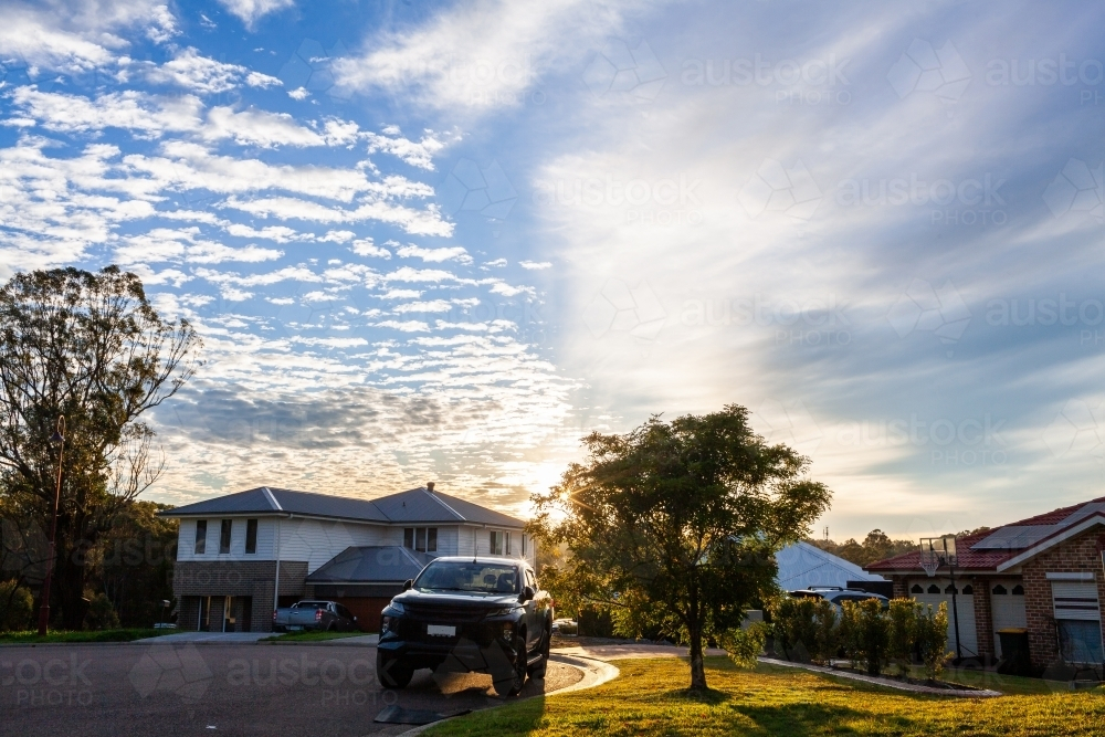 Image of Sunrise over suburban street with car tree and house below ...