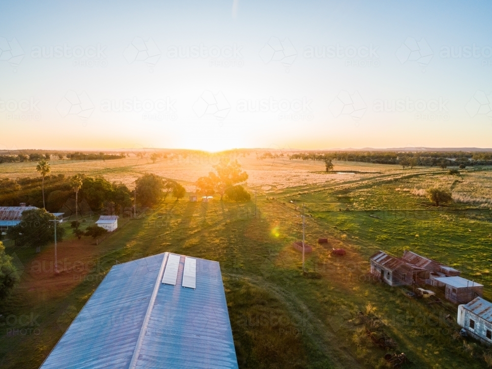Image of Sunset over farm shed with two rows of solar panels in wide ...