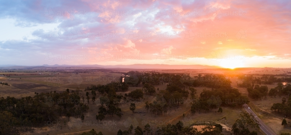 Image of Sunset with colourful clouds over dry paddocks - Austockphoto