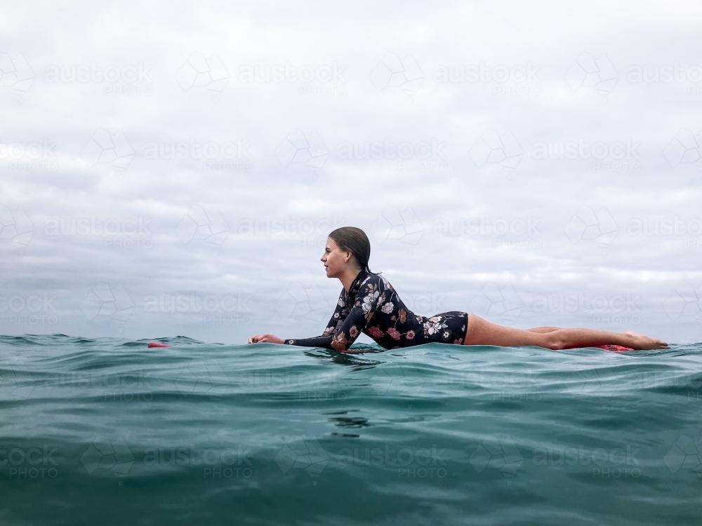 Image of Surfing Teenage girl lying on red surfboard in ocean wearing ...