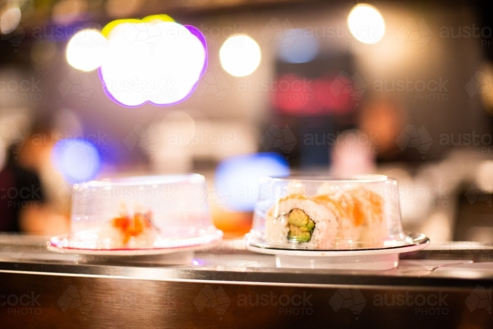 Image of sushi train plates travelling on a conveyer - Austockphoto