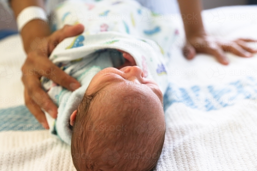 Image of Swaddled newborn lying on bed - Austockphoto