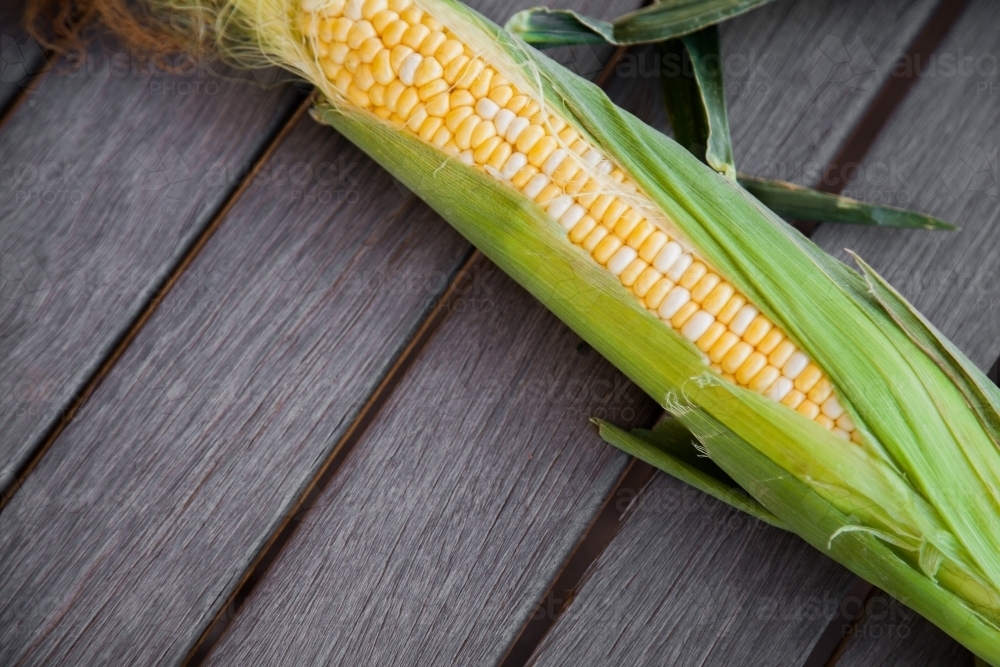 Image of Sweet corn with green husk on wooden table background ...