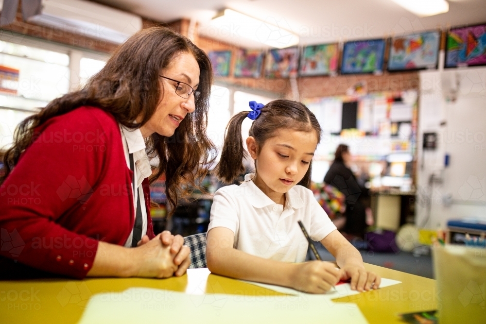 Image of Teacher Helping Young Schoolgirl to Draw - Austockphoto