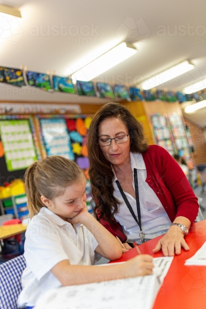 Image of Teacher Helping Young Student in Classroom - Austockphoto