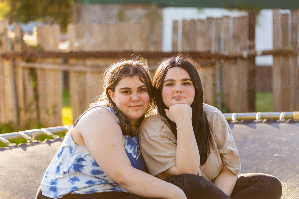 Image Of Teen Aboriginal Sisters Sitting Together On Trampoline In
