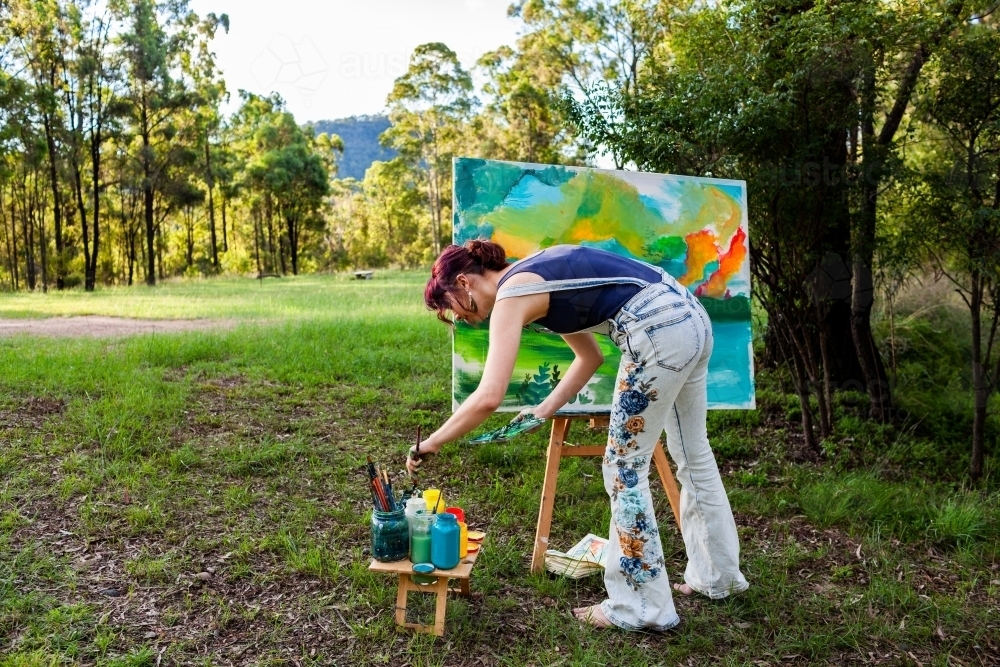 Image of Teen artist with paint pots and brushes working on artwork in ...