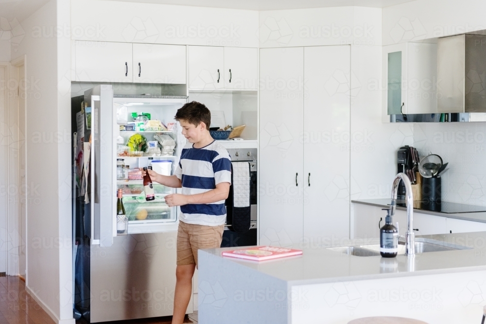 Image of teen boy getting a snack from the fridge - Austockphoto
