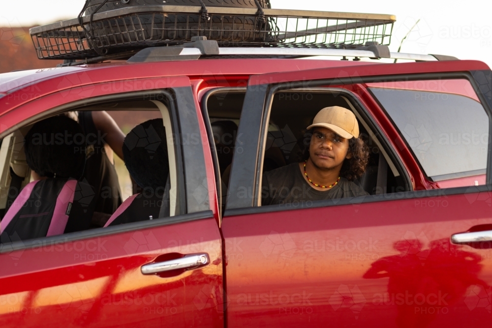 Image of teen boy on back seat of red family car with spare tyre on ...