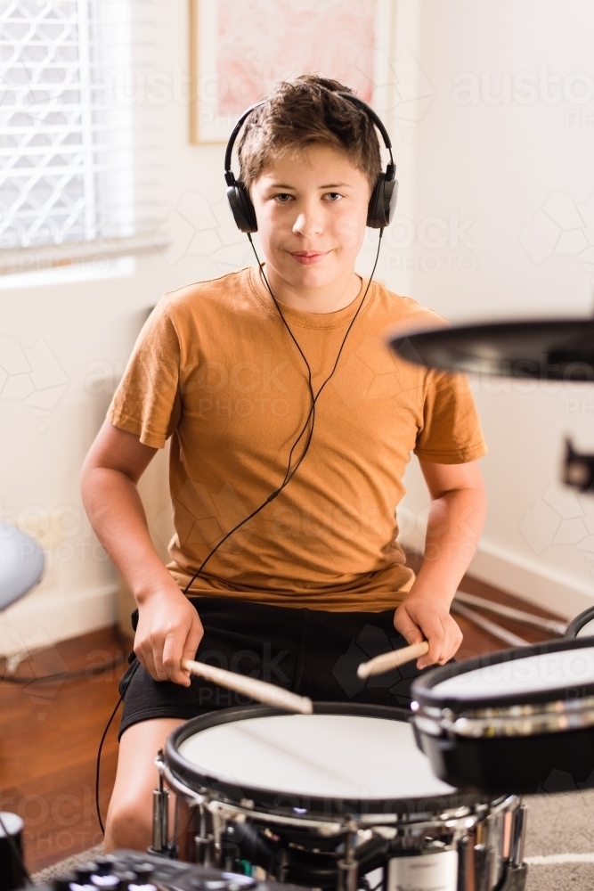 Image of teen boy practising drums at home - Austockphoto