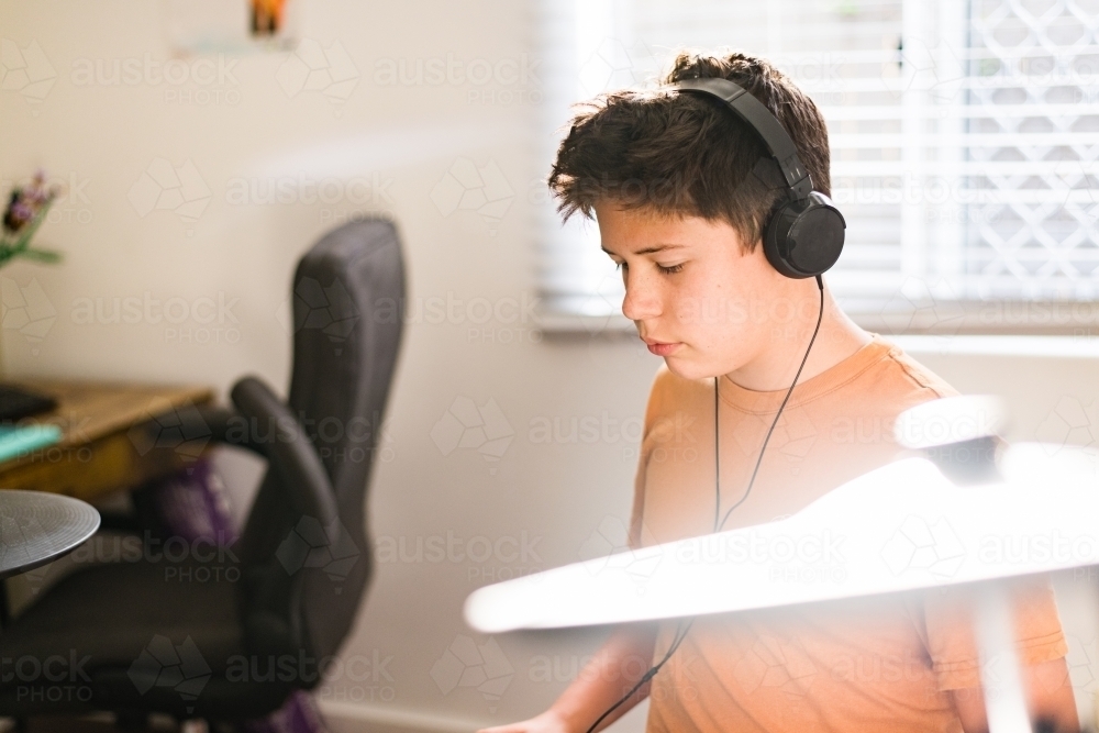 Image of teen boy practising drums at home - Austockphoto