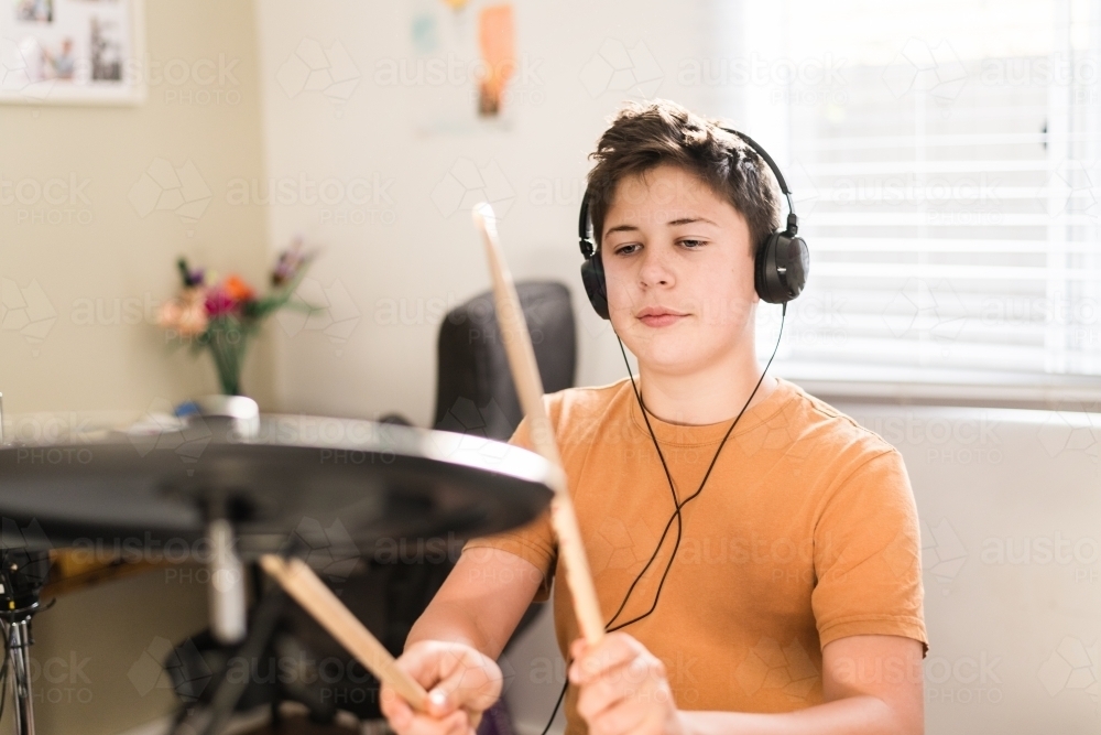 Image of teen boy practising drums at home - Austockphoto