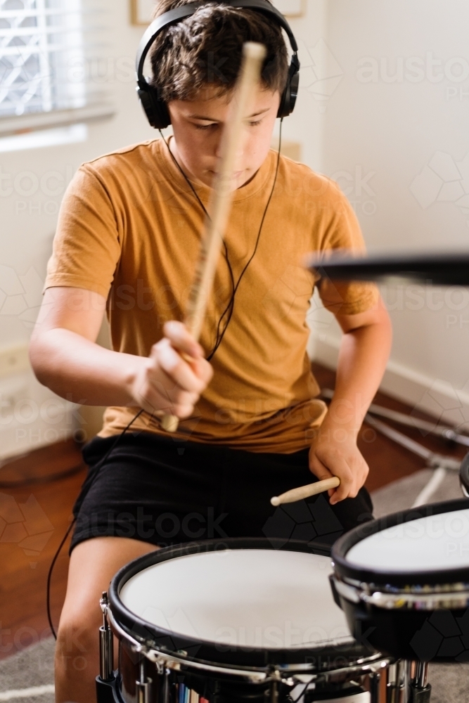 Image of teen boy practising drums at home - Austockphoto