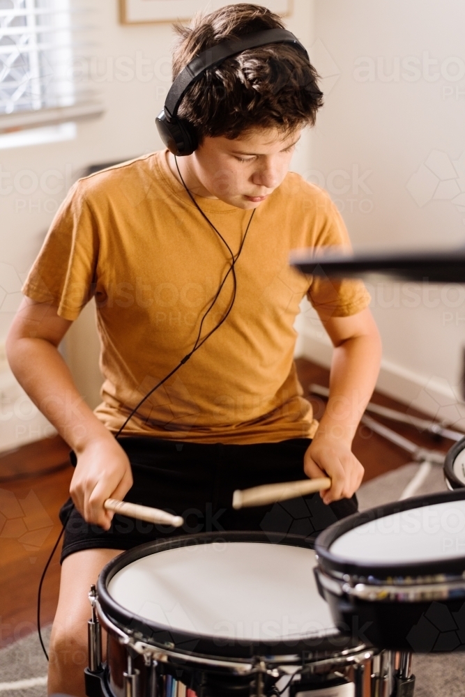 Image of teen boy practising drums at home - Austockphoto