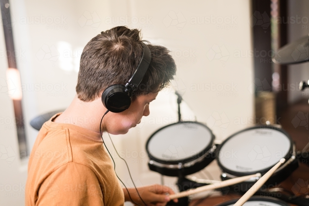 Image of teen boy practising drums at home - Austockphoto