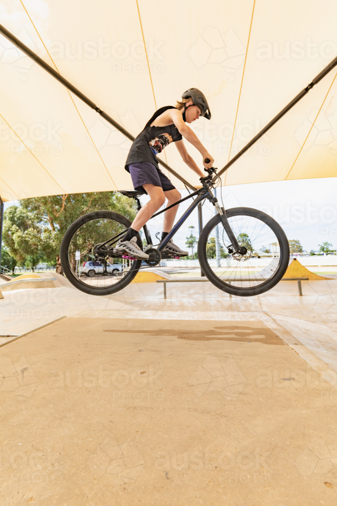 Image of Teen boy riding mountain bike at skate park - Austockphoto