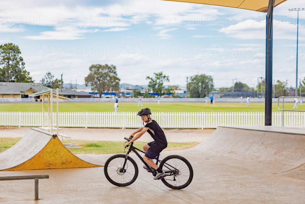 Image of Teen boy riding mountain bike at skate park - Austockphoto