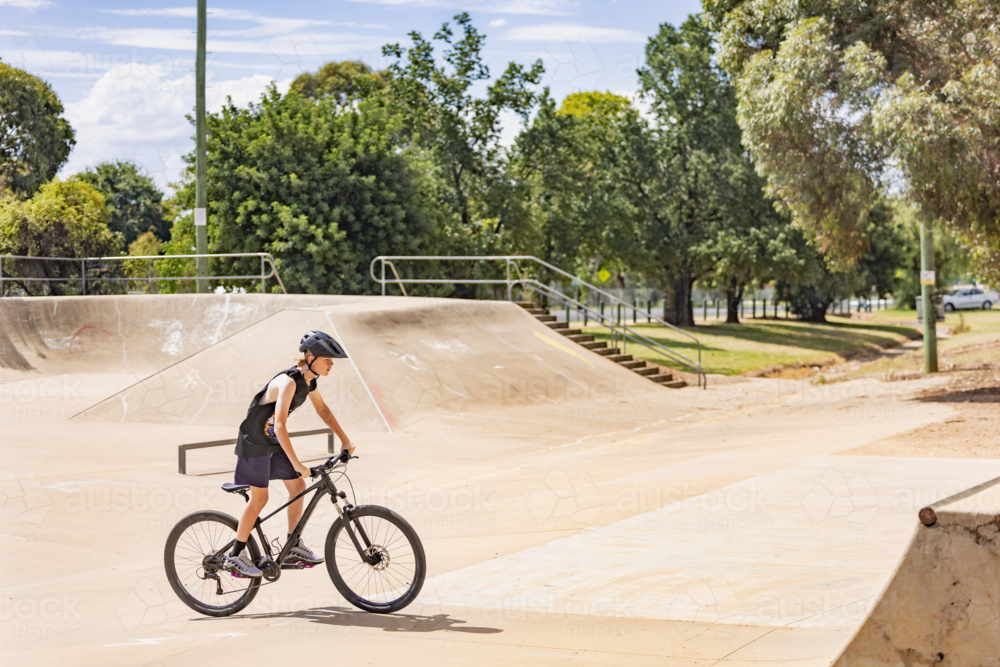 Image of Teen boy riding mountain bike at skate park - Austockphoto