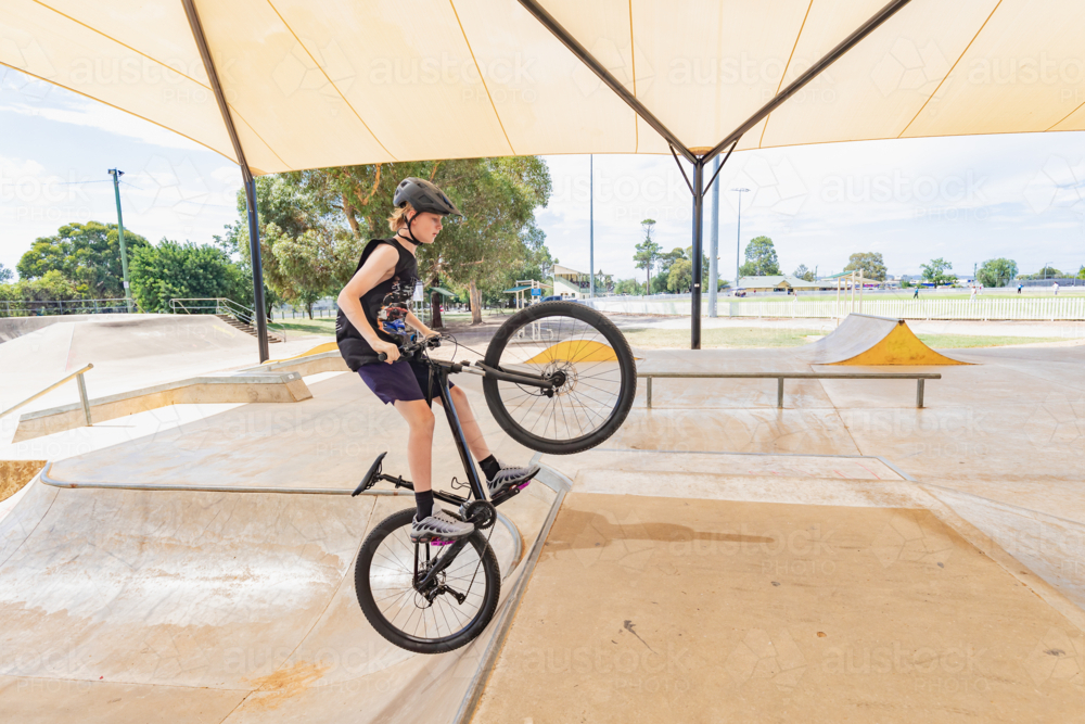 Image of Teen boy riding mountain bike at skate park - Austockphoto