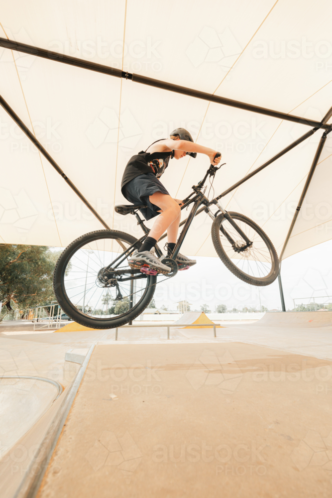 Image of Teen boy riding mountain bike at skate park - Austockphoto