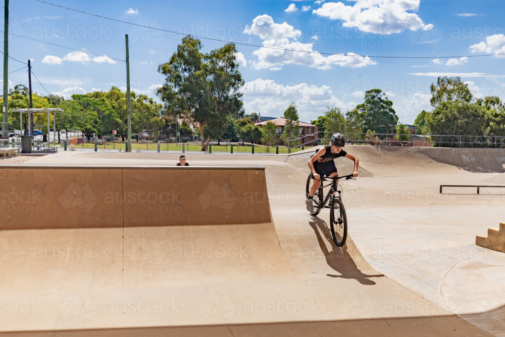 Image of Teen boy riding mountain bike at skate park - Austockphoto