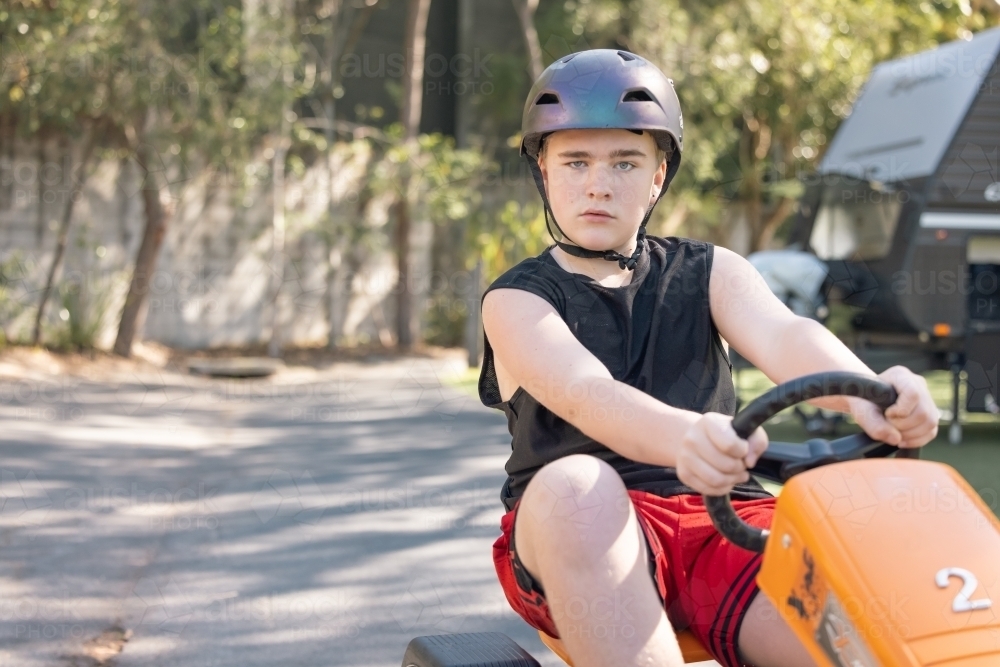Image of Teen boy riding pedal cart at caravan park - Austockphoto