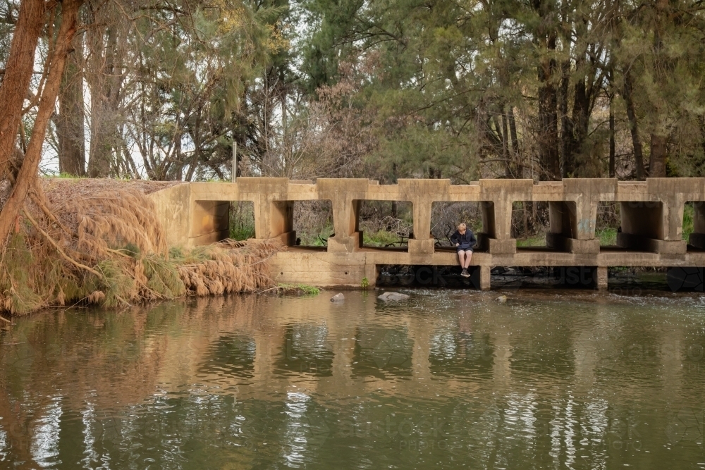 Image of Teen boy sitting under low bridge over the Cudgegong River in ...