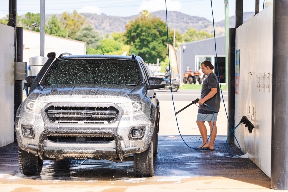 Image of Teen boy washing vehicle in self-service car wash bay ...