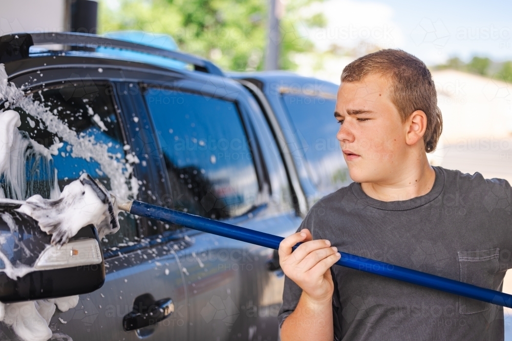 Image of Teen boy washing vehicle in self-service car wash bay ...