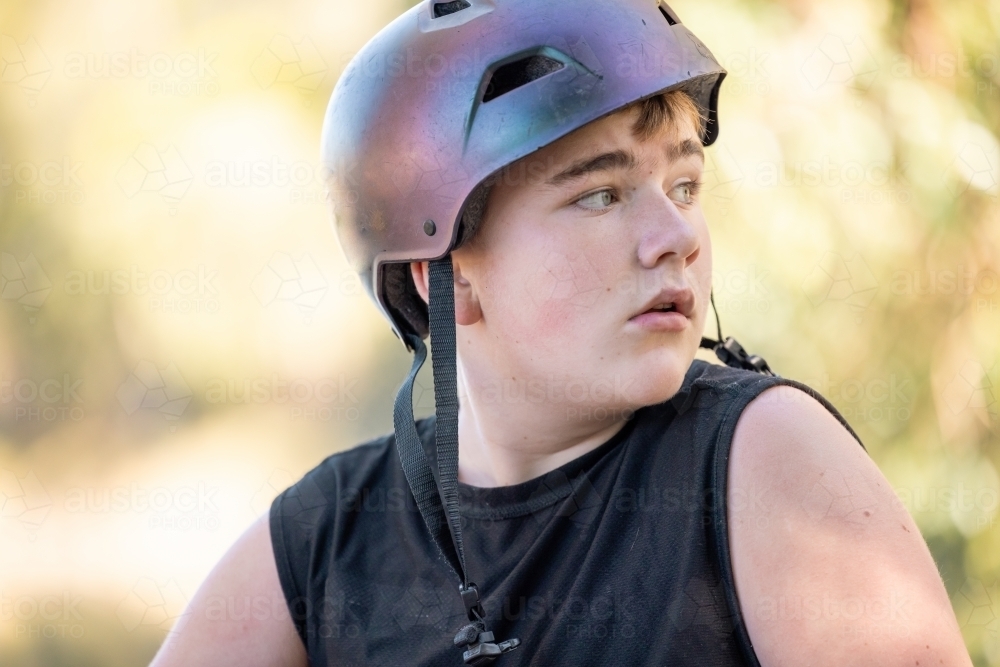 Image of Teen boy wearing unclipped skate helmet - Austockphoto
