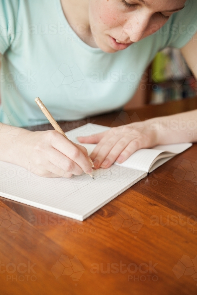 Image of Teen girl doing math work on the table at home - Austockphoto