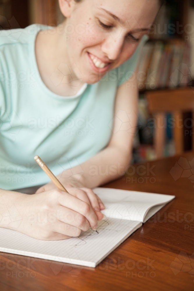 Image of Teen girl doing math work on the table at home - Austockphoto
