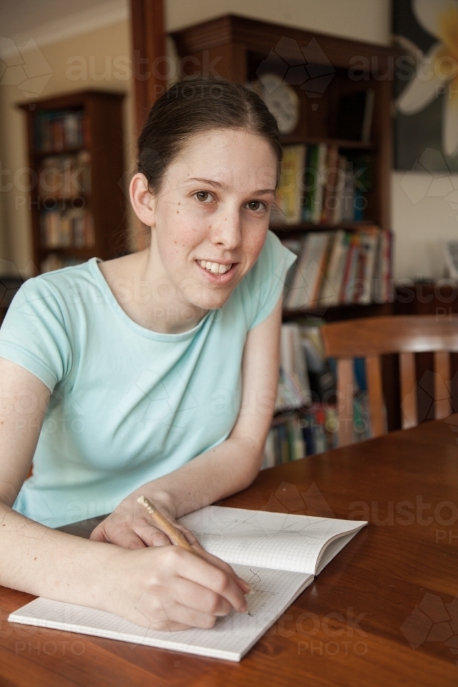 Image of Teen girl doing math work on the table at home - Austockphoto