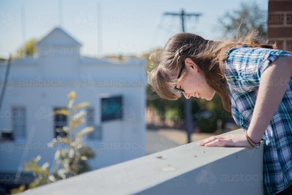 Image of Teen girl looking off a sunlit balcony - Austockphoto