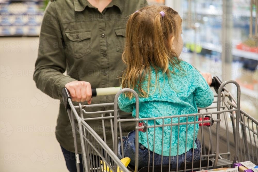 Image of Teen girl pushing little sister in shopping trolley - Austockphoto