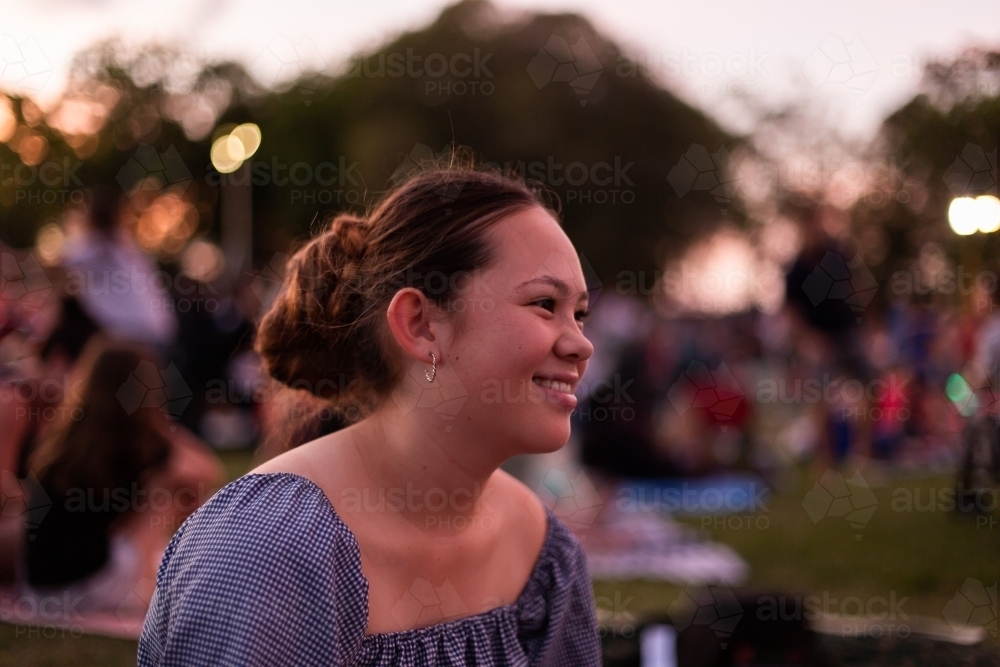 Image of teen girl smiling at an outdoor concert at dusk - Austockphoto