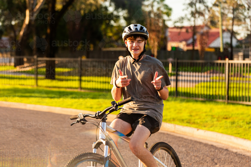 Image of Teen on bike doing fingerguns on street at sunset showing off - Austockphoto