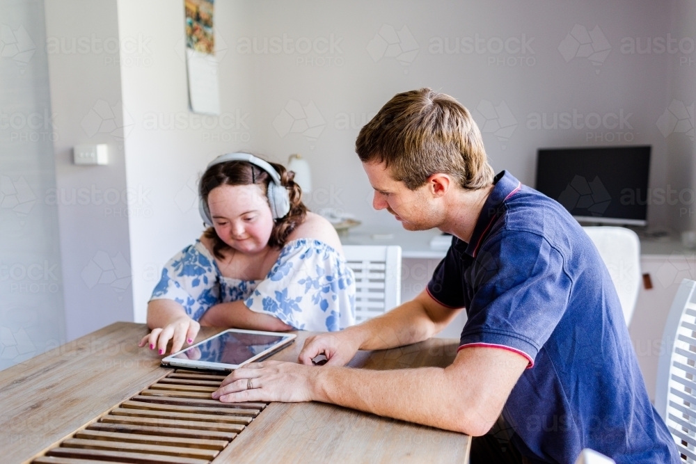 Image of Teen wearing headphones talking with adult disability support ...