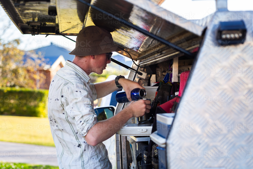 Image of teen worker handyman apprentice standing by ute making tea ...