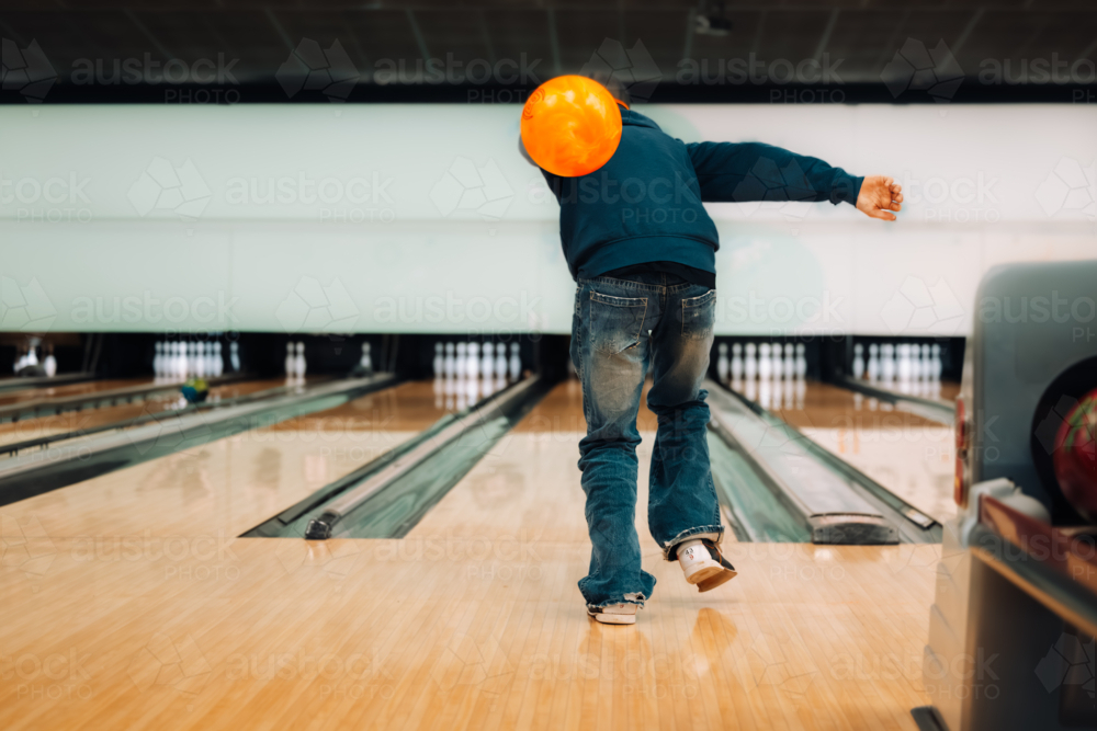 Image of Teenage boy about to release ball while ten pin bowling ...