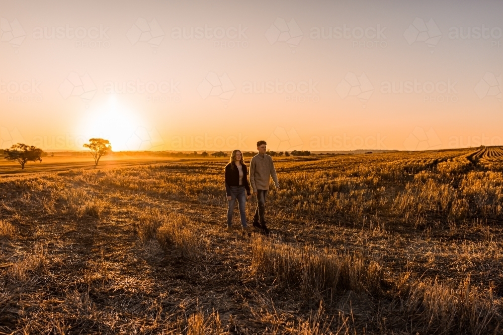 Image of Teenage boy and girl walking together through rural grassland ...
