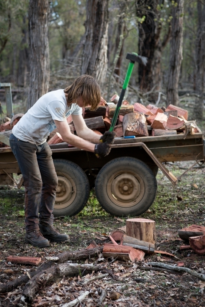 Image of Teenage boy chopping wood in a forest - Austockphoto