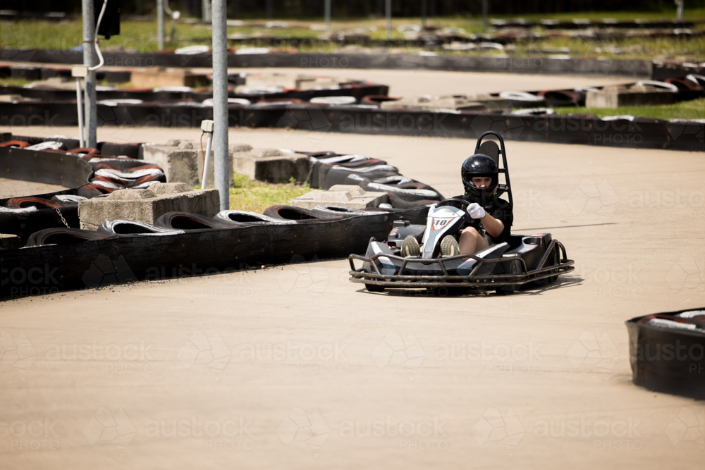 Image of Teenage boy driving go kart around outdoor track - Austockphoto