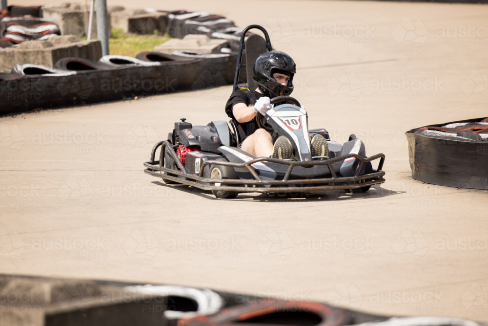 Image of Teenage boy driving go kart around outdoor track - Austockphoto