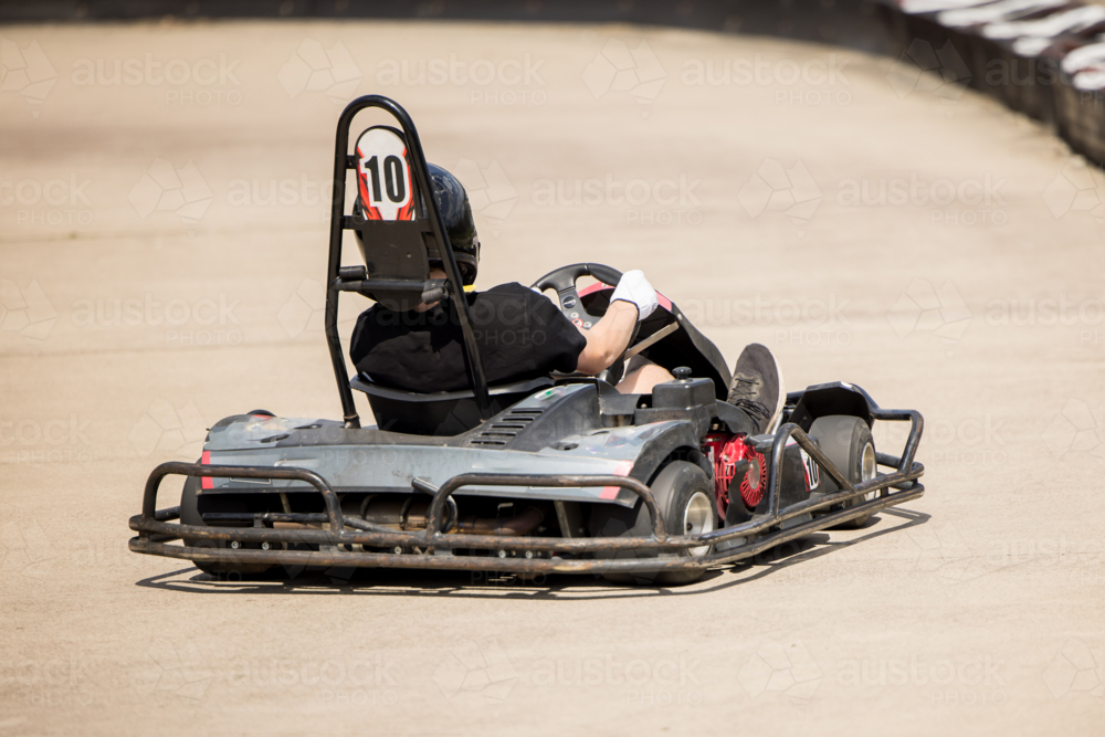 Image of Teenage boy driving go kart around outdoor track - Austockphoto