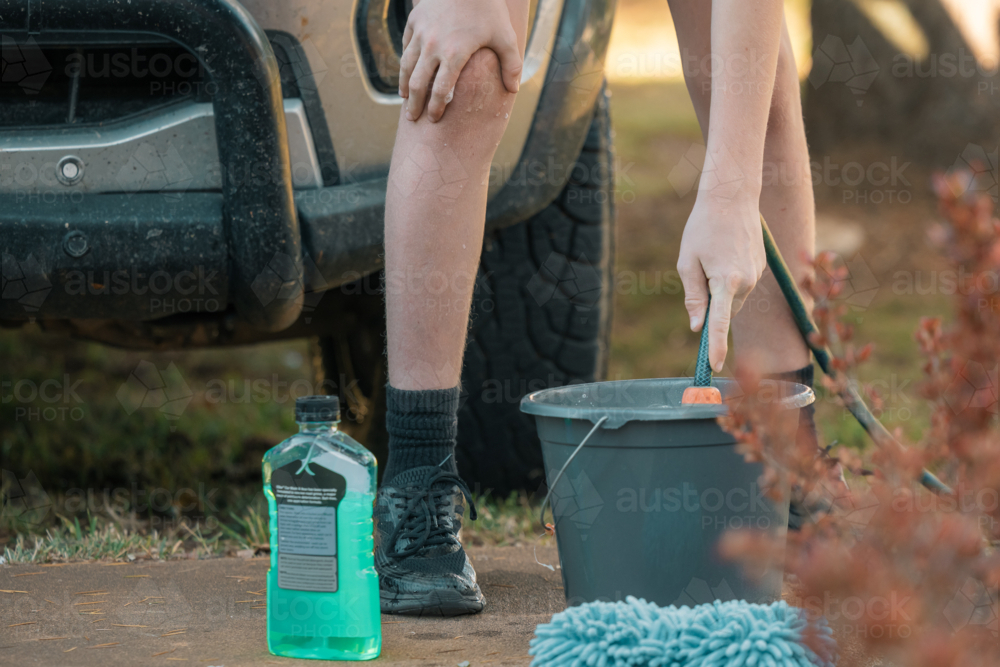 Image of Teenage boy filling bucket with soapy water preparing to wash ...