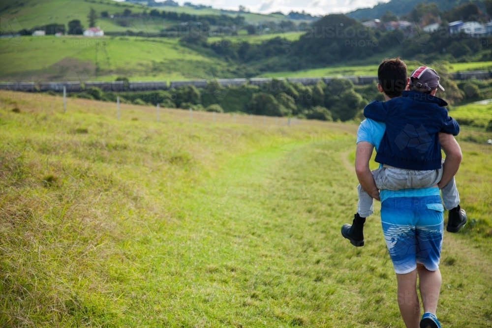 Image of Teenage boy giving a piggyback ride to kid on a bushwalk ...