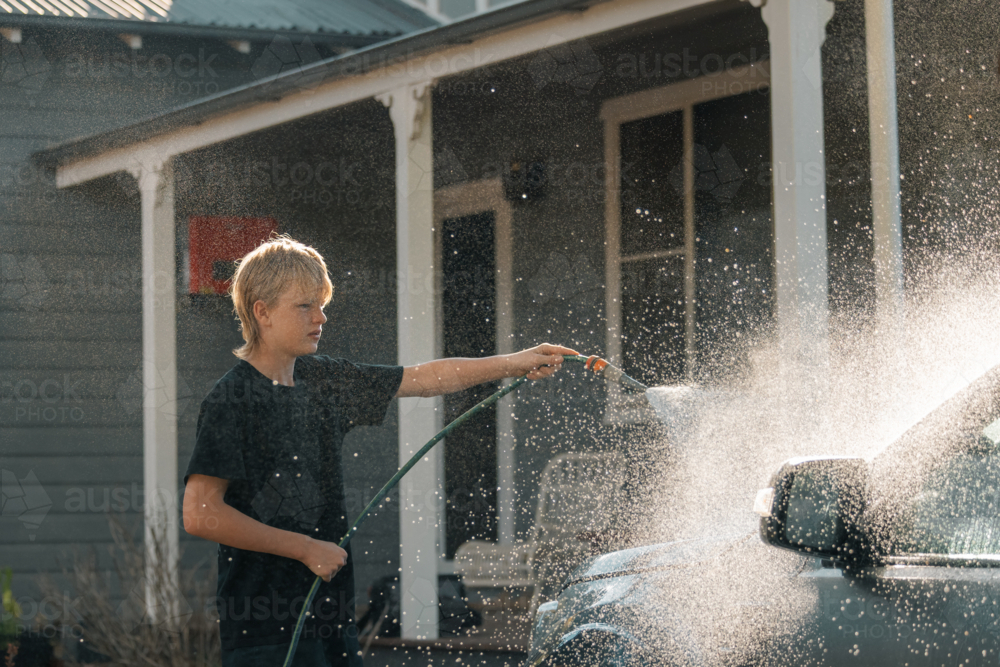 Image of Teenage boy hosing down vehicle in preparation for cleaning ...
